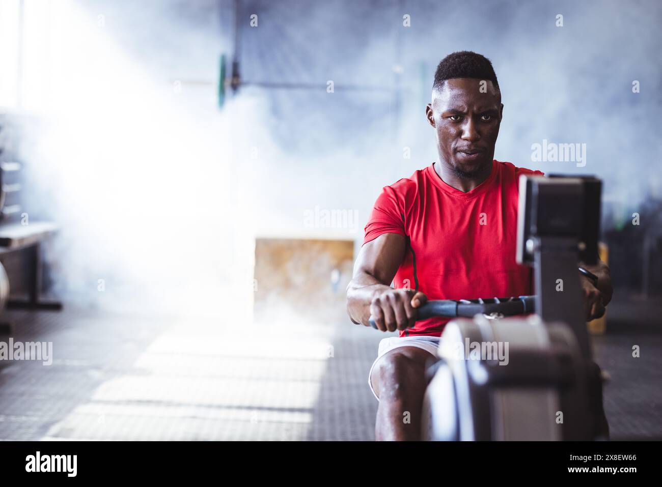 At gym, African American man working out on rowing machine, focused and ...