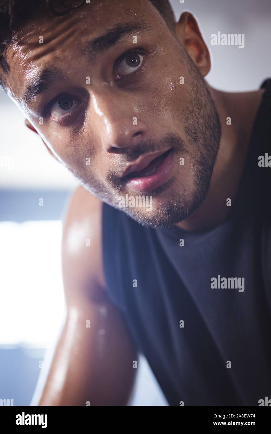 Fit biracial man sweating during intense workout at gym in bright ...