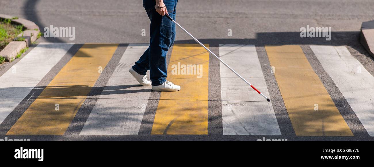 Close-up of the legs of a blind woman crossing the road at a crosswalk ...