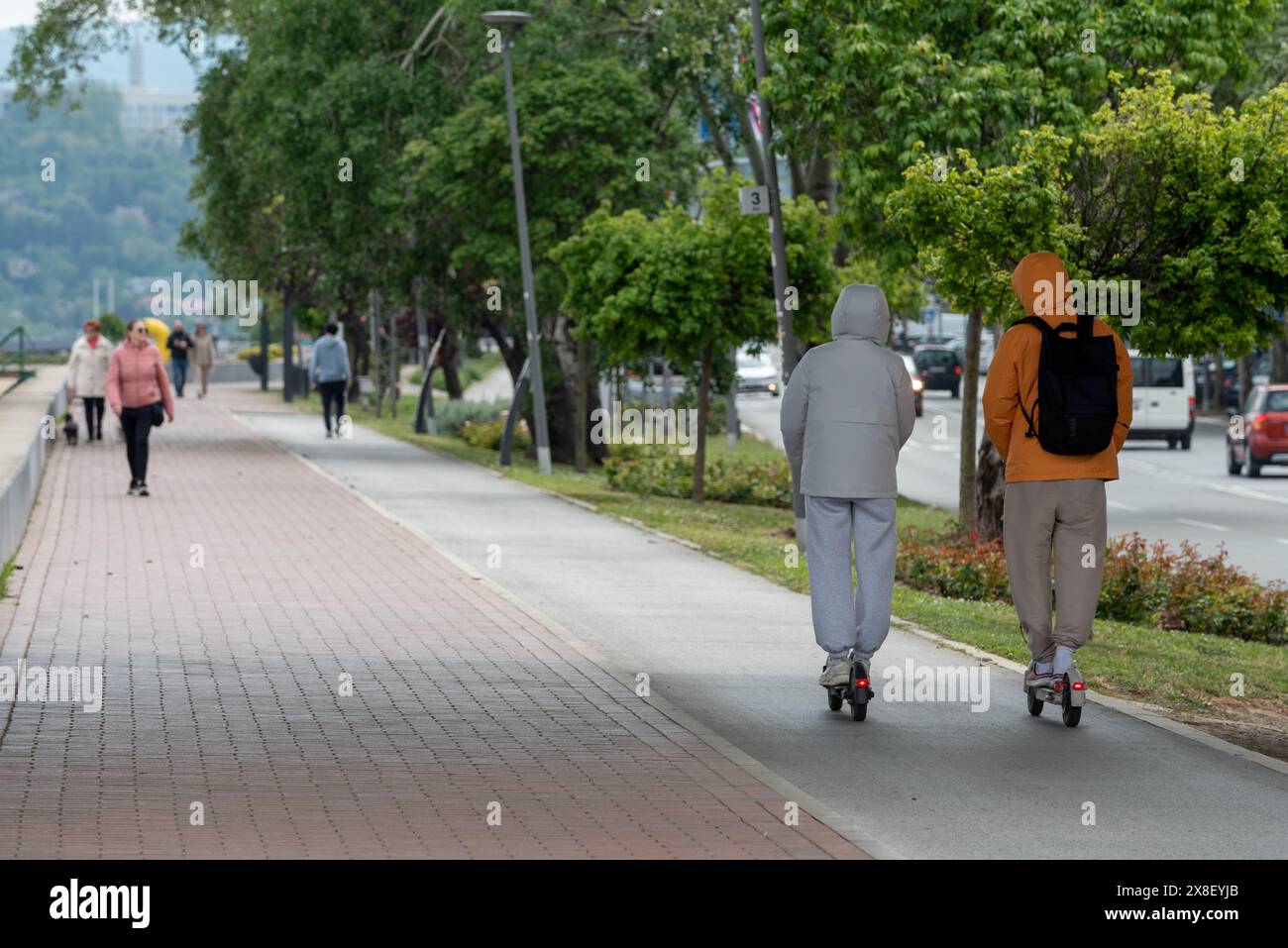 Two people ride their electric scooters along the promenade in Novi Sad ...