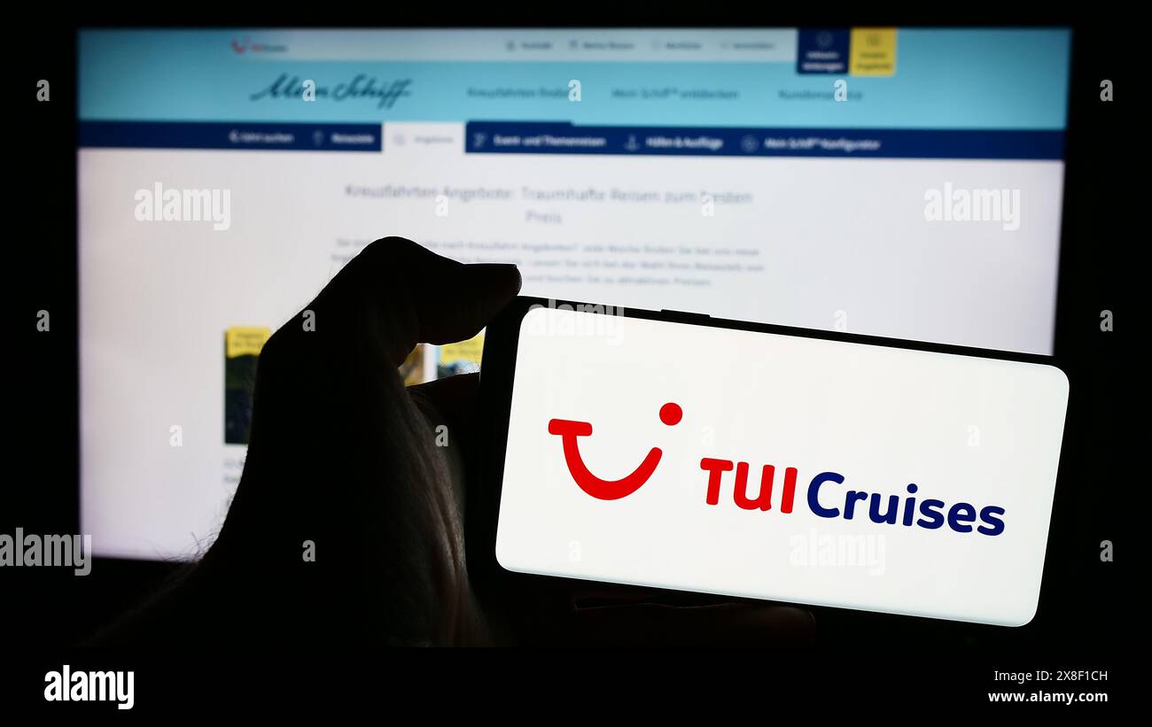 Person holding mobile phone with logo of German cruise line company TUI ...