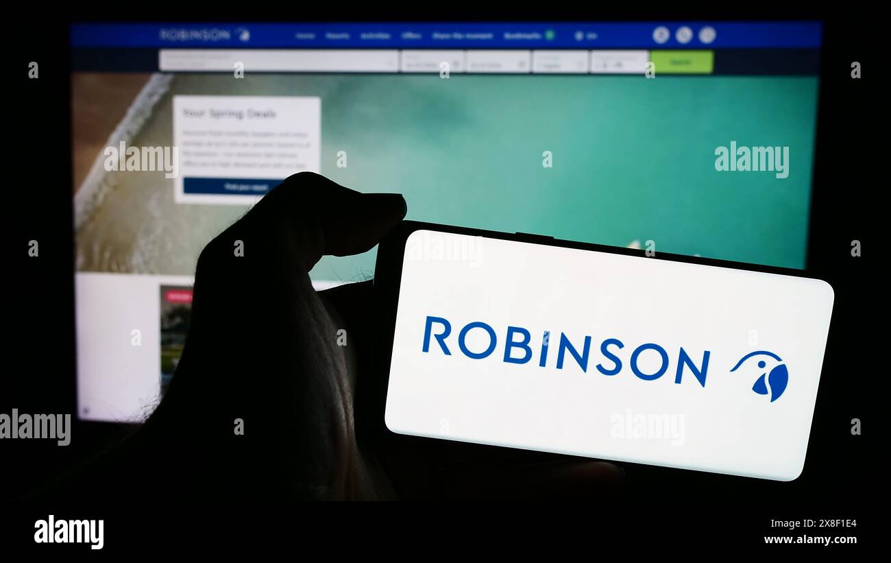 Person holding mobile phone with logo of German hospitality company Robinson Club GmbH in front ...