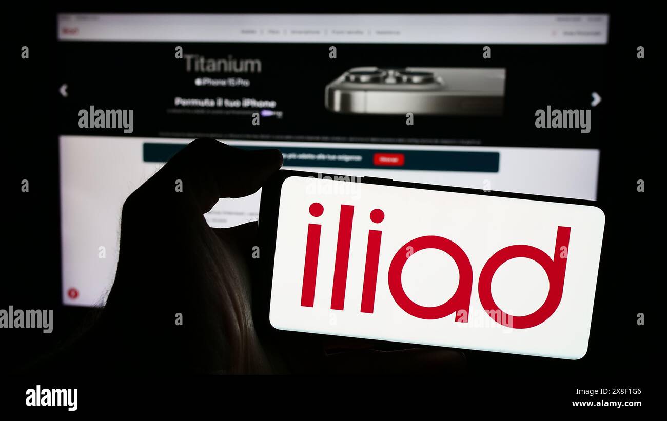 Person holding mobile phone with logo of telecommunications company ...