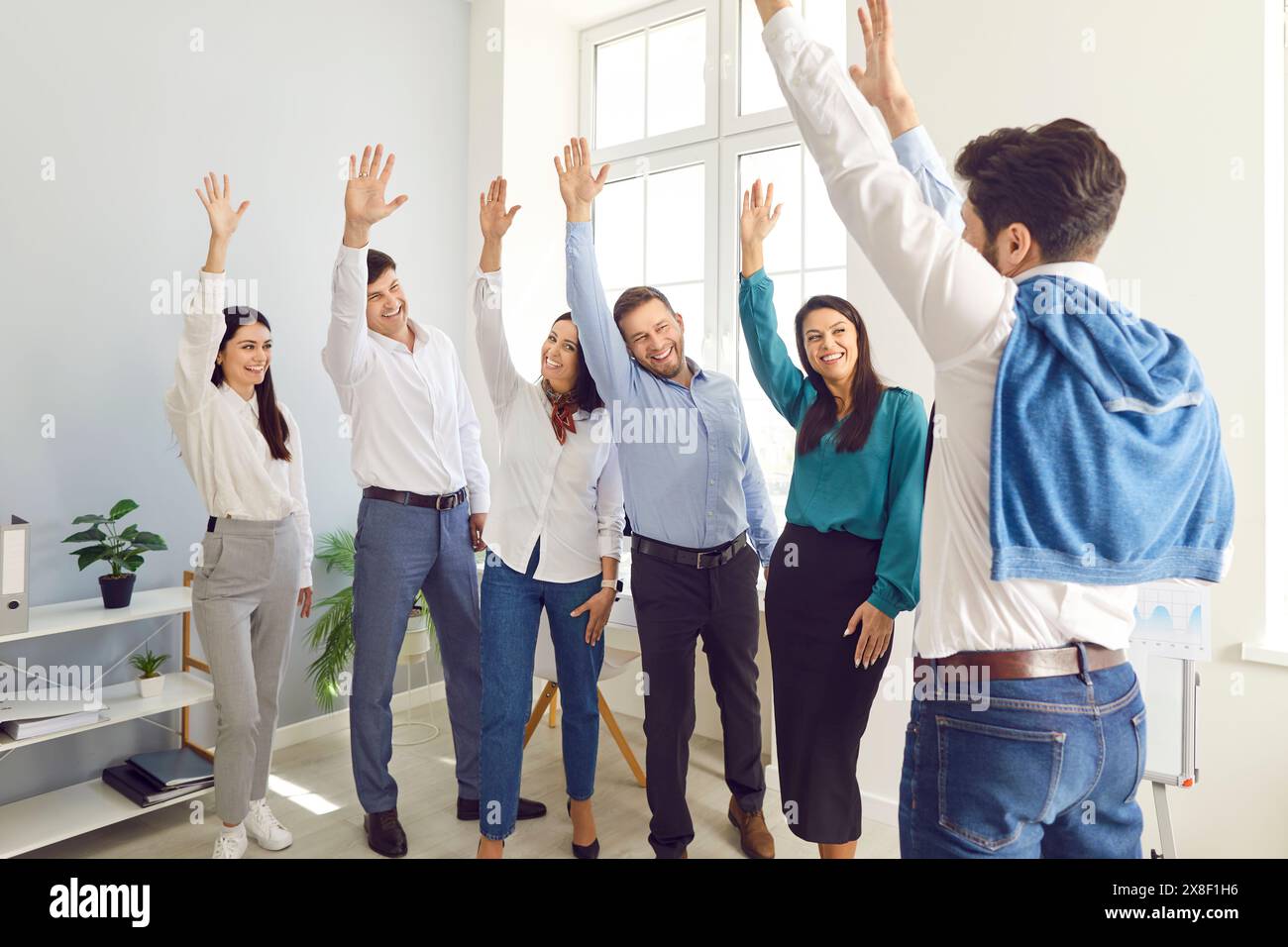 Young cheerful company employees raising hands to vote at the ...