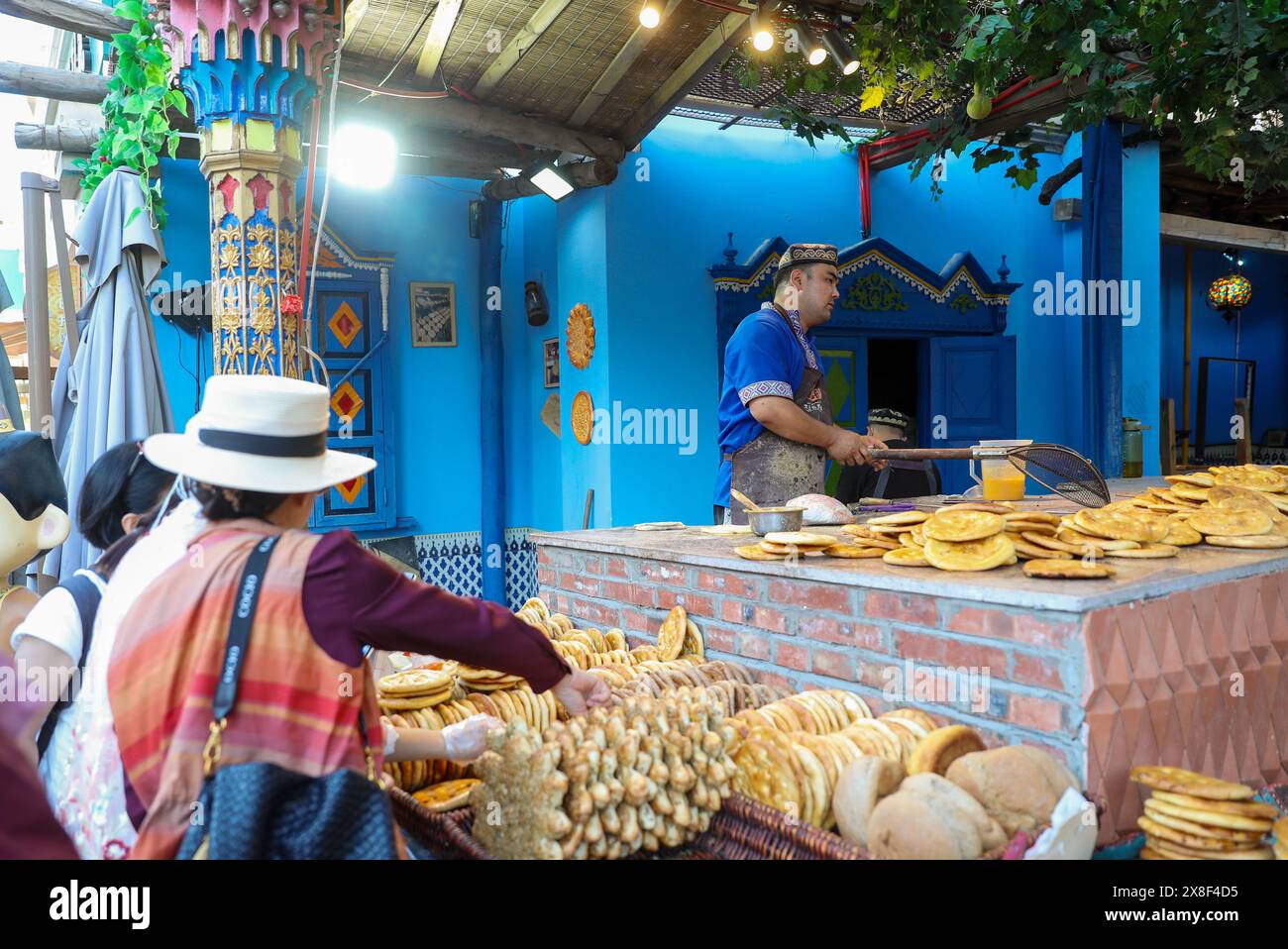 Urumqi, China. 25th May, 2024. A vendor is making naan bread at the ...
