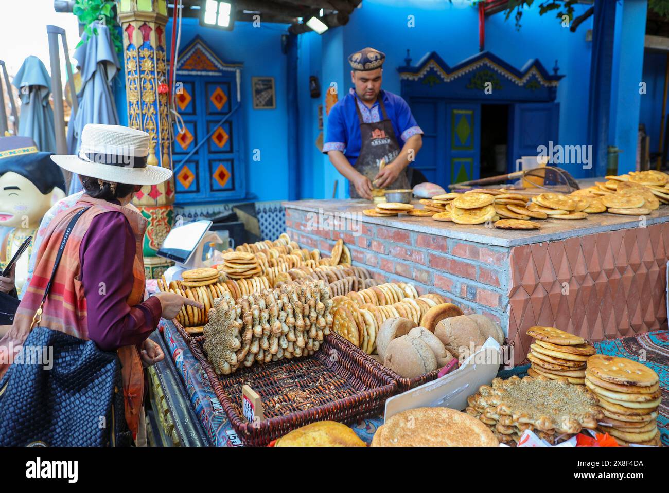 Urumqi, China. 25th May, 2024. A vendor is making naan bread at the ...