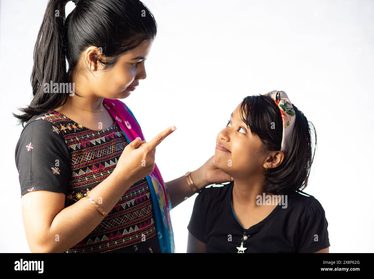 An Indian mother scolding and pulling her daughter's ear on white ...