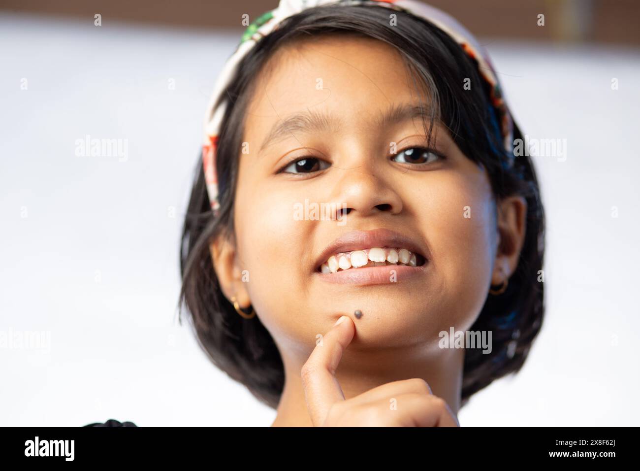 A pretty Indian girl child showing her mile on chin with smiling face ...