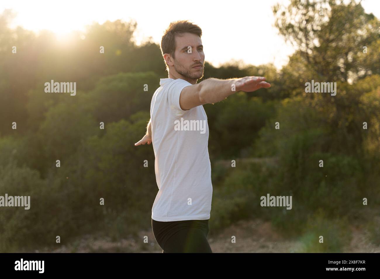 A man stretches his arms to do physical activity and yoga outdoors ...