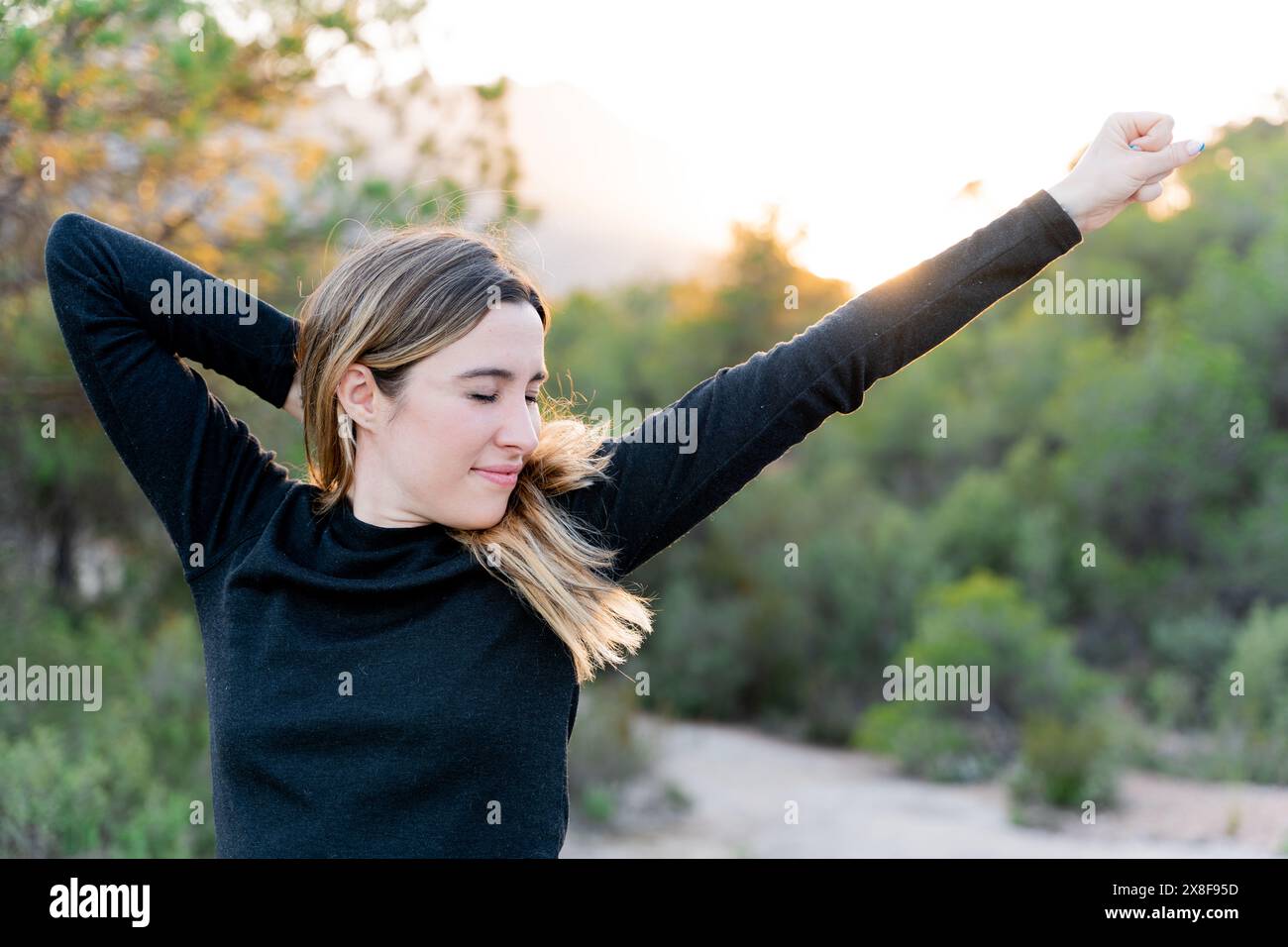 Portrait of woman doing morning body stretches in nature Stock Photo ...