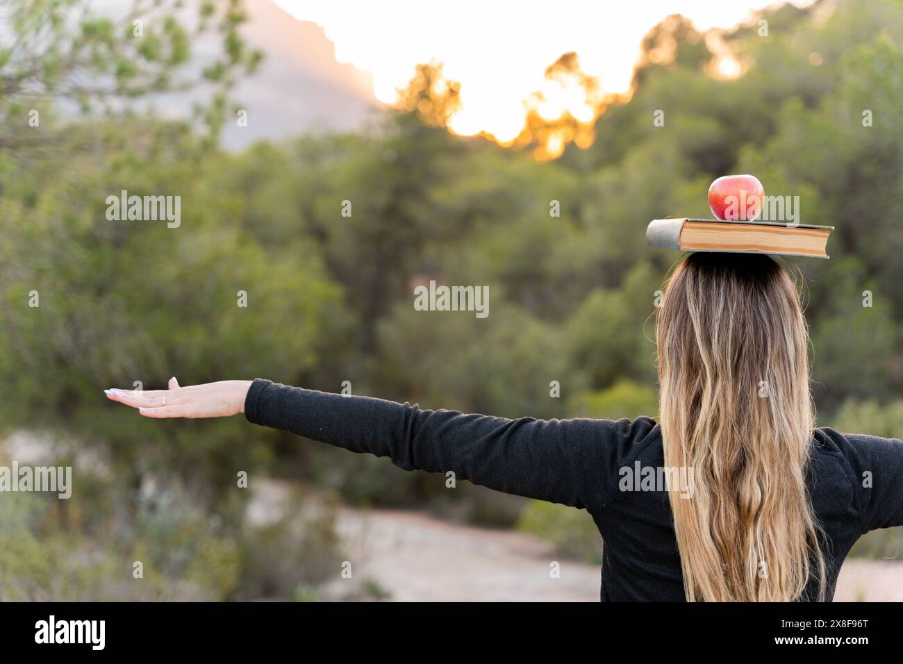 Woman on her back with a book and an apple on her head, healthy habits ...