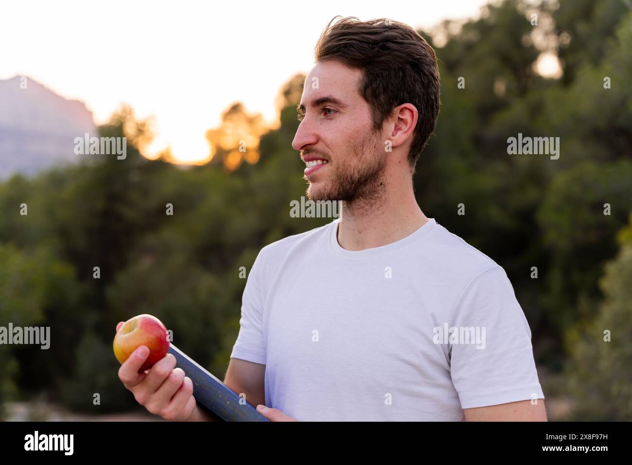 Man smiling with an apple and a book in his hand. Concept of healthy ...