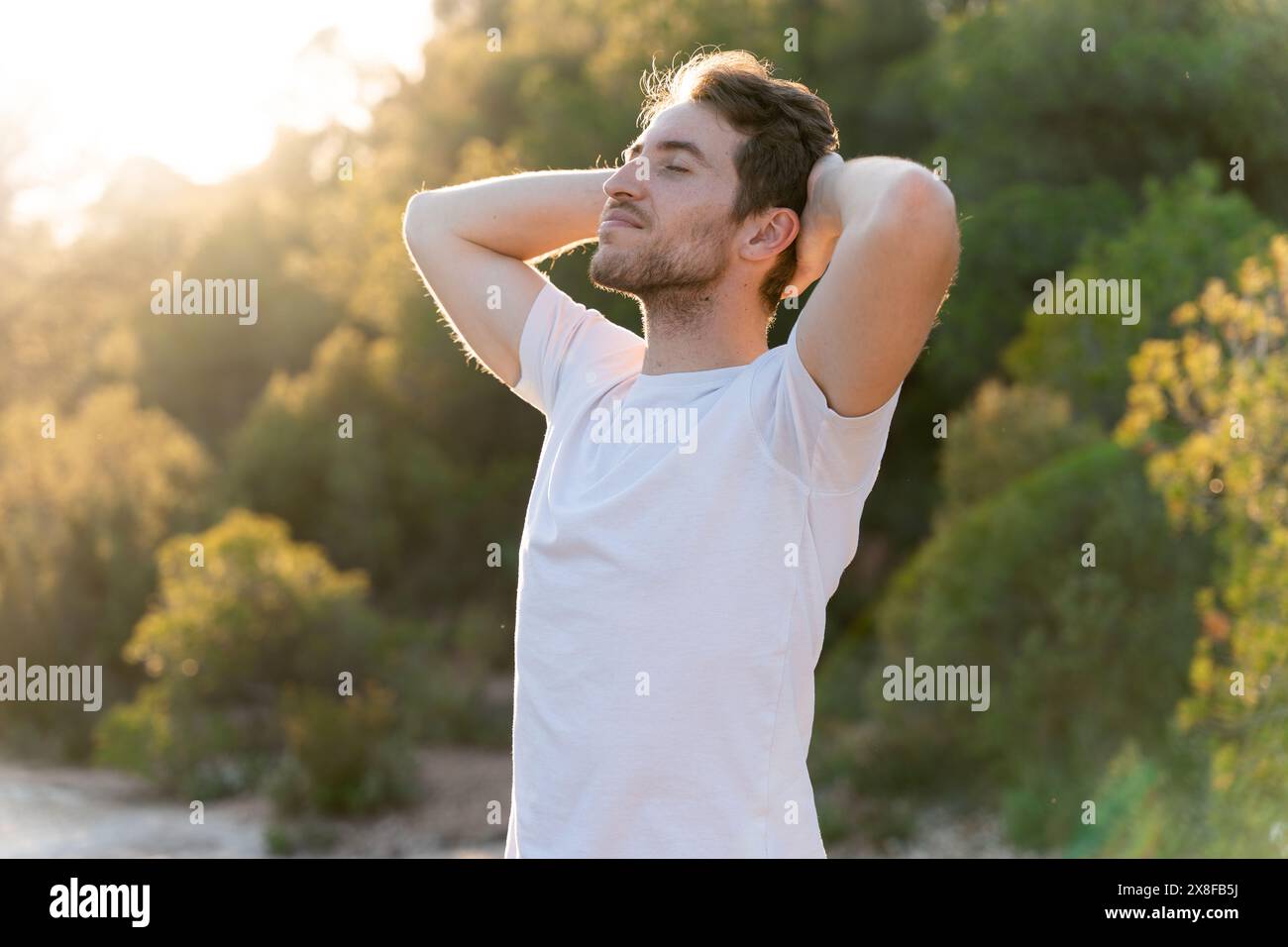An attractive man breathes fresh air from nature at sunset. Healthy ...
