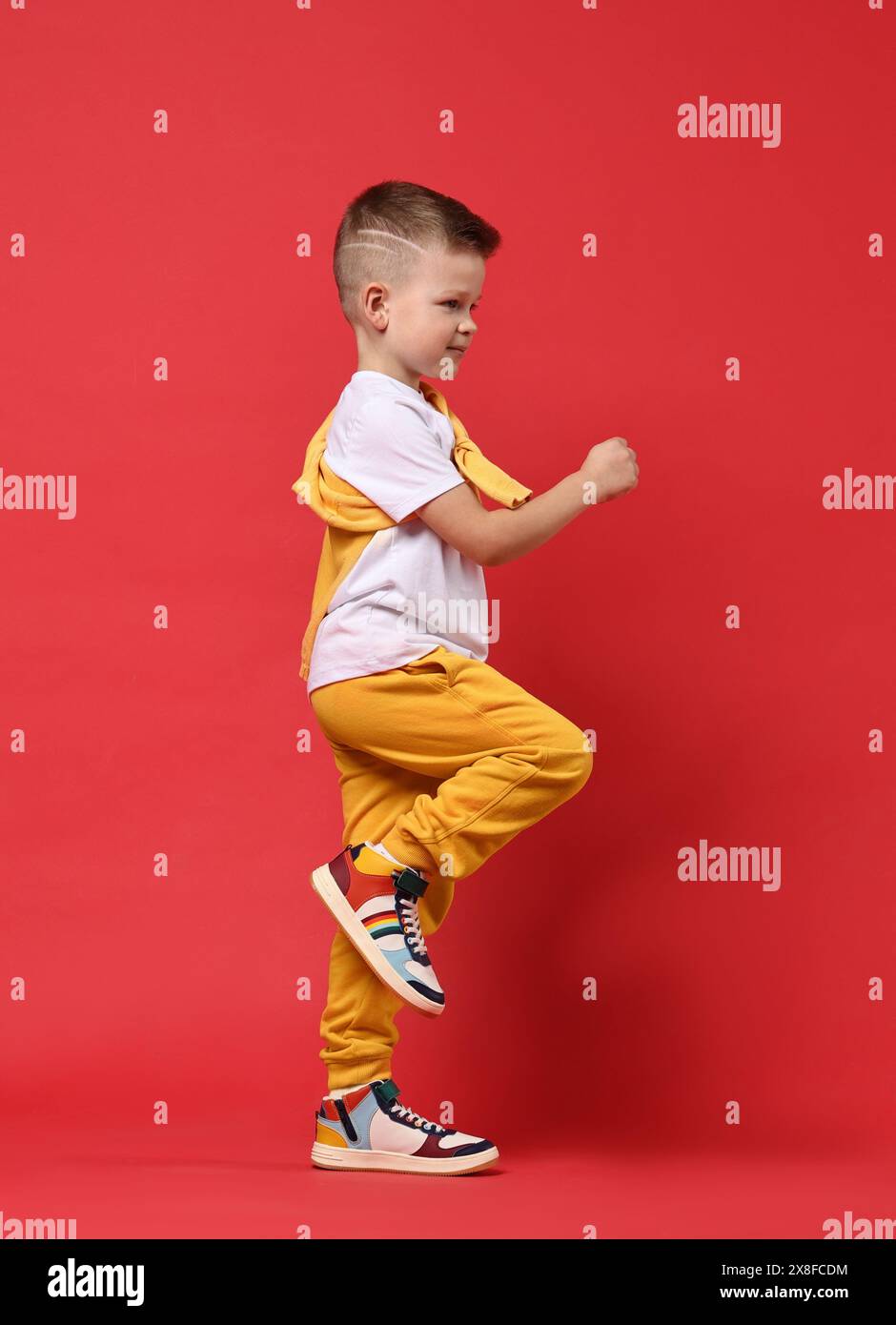 Happy little boy dancing on red background Stock Photo - Alamy