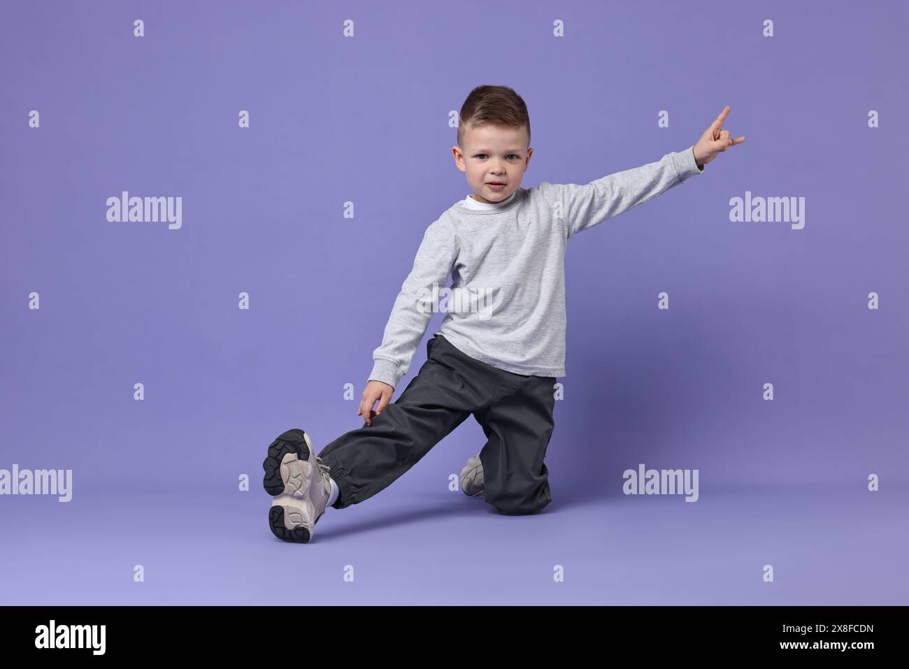 Happy little boy dancing on violet background Stock Photo - Alamy