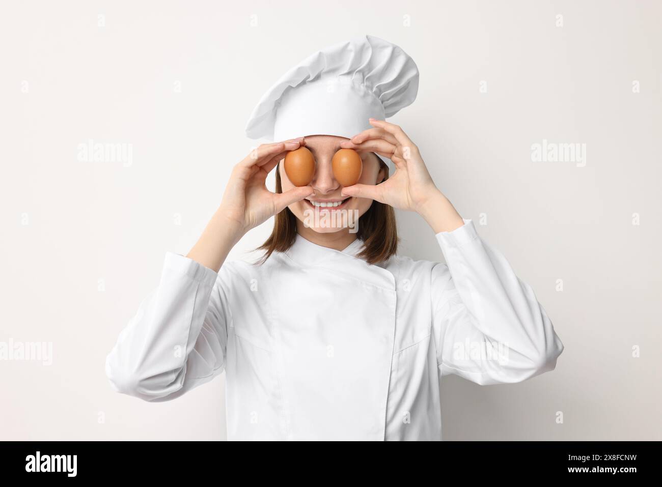 Professional chef with chicken eggs having fun on light background ...