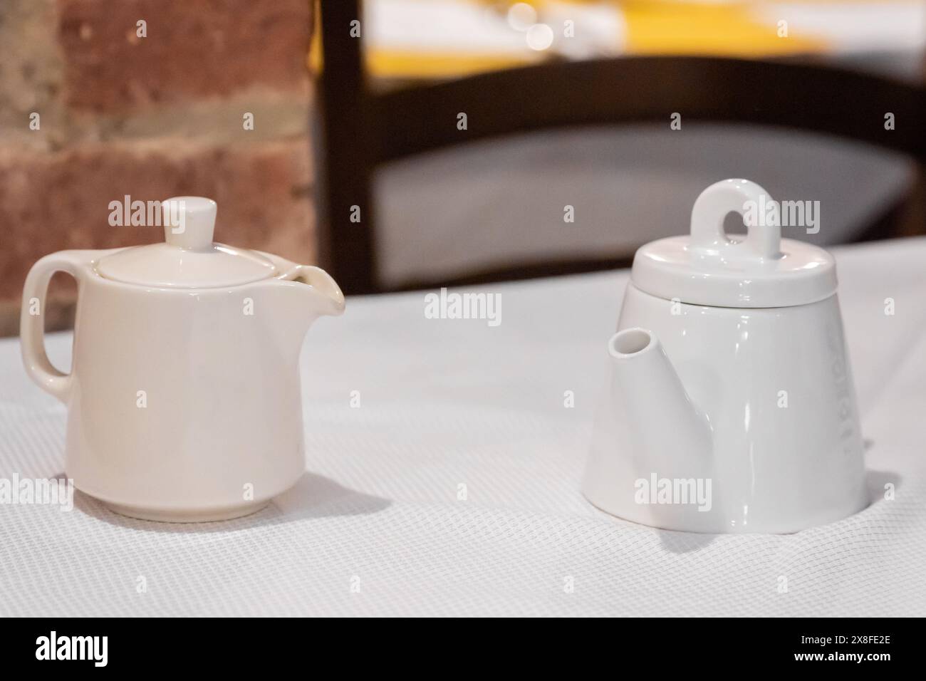 Two teapots on table with brick wall background Stock Photo - Alamy