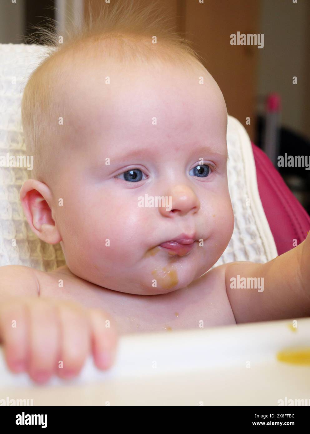 A cute baby with blue eyes has broccoli puree smeared all over their ...