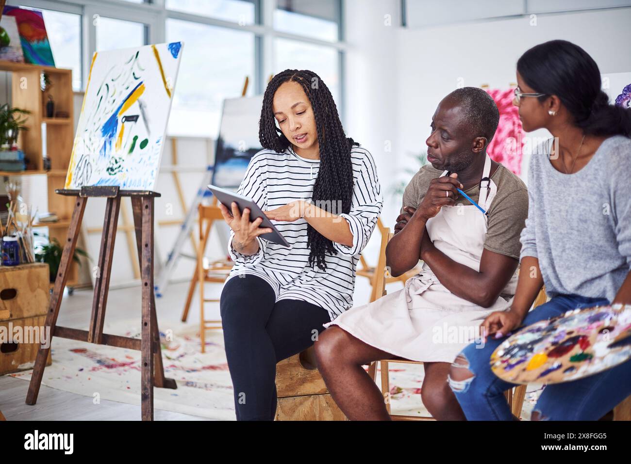 Creative people, tablet and conversation in art studio with canvas and ...