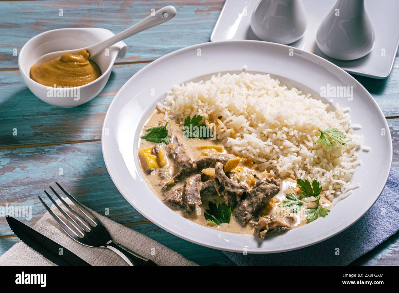 Beef Stroganoff with rice on plate with mustard on table Stock Photo ...