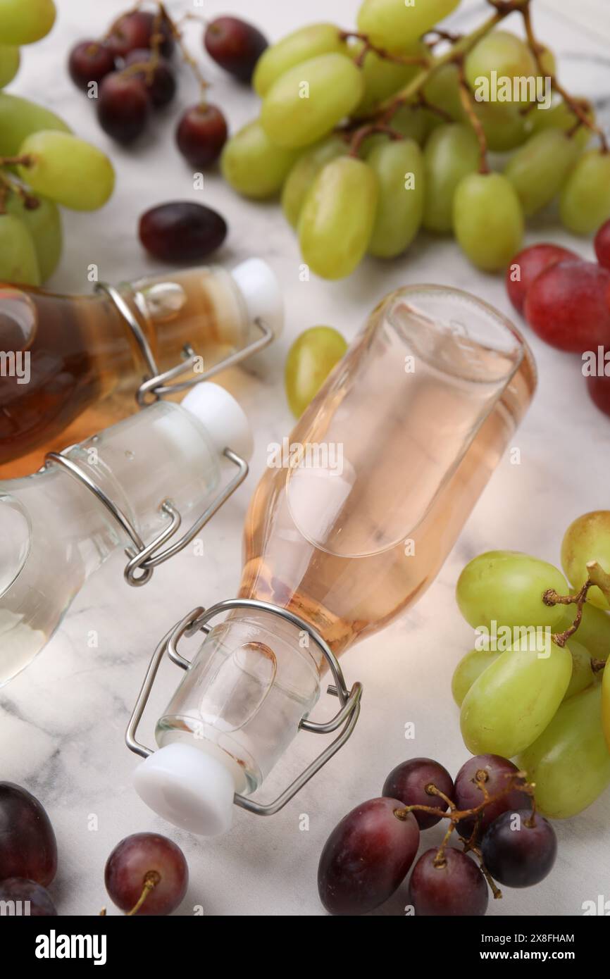 Different types of vinegar in bottles and grapes on light table ...