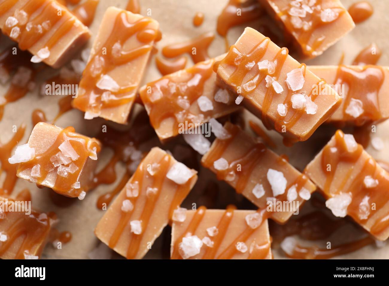 Yummy candies with caramel sauce and sea salt on parchment paper, flat ...