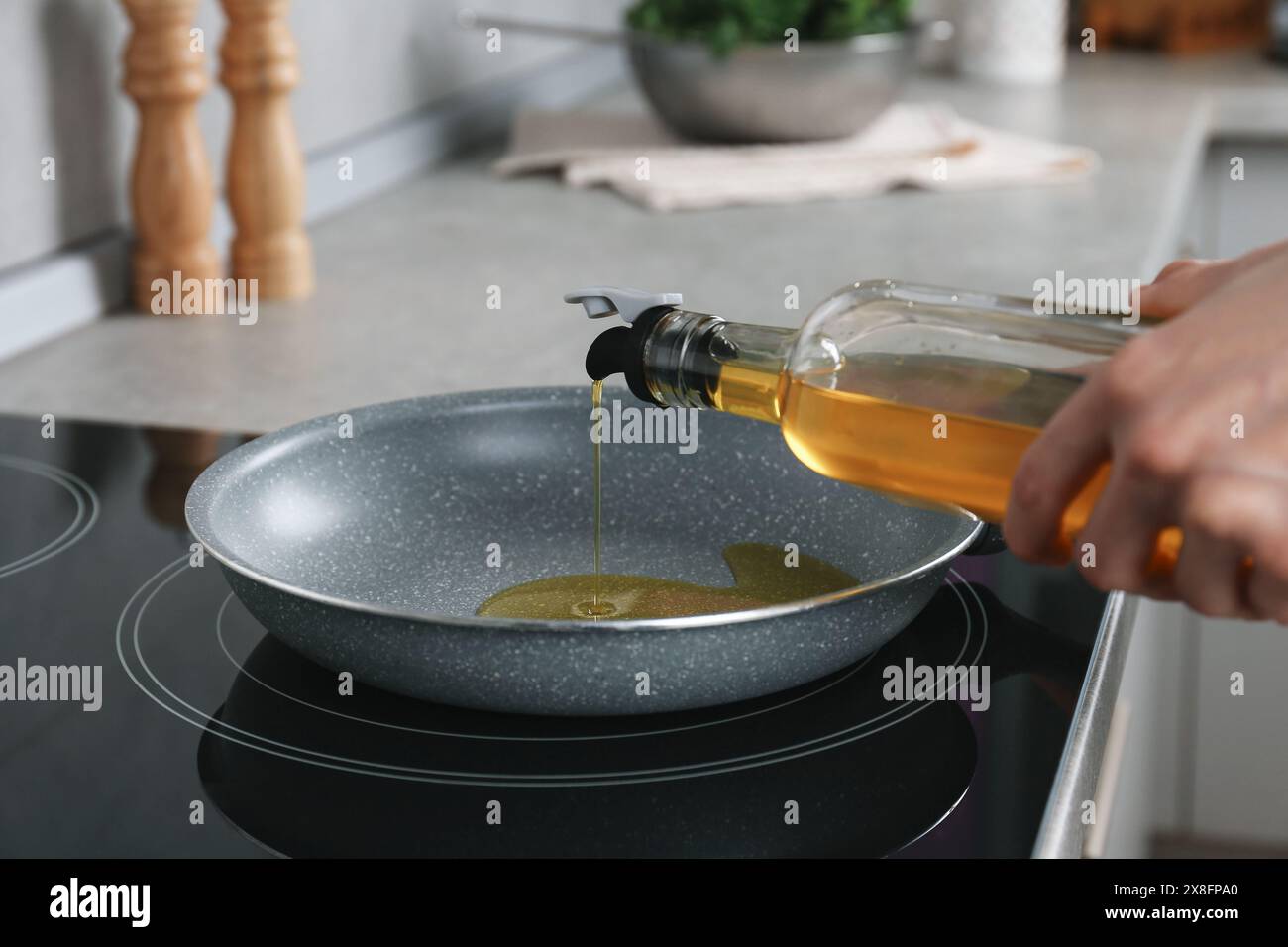 Vegetable fats. Woman pouring cooking oil into frying pan on stove in ...