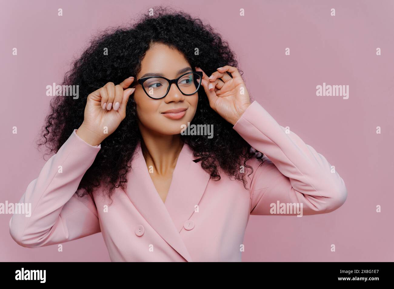 Reflective woman adjusting her glasses, lost in thought with a ...