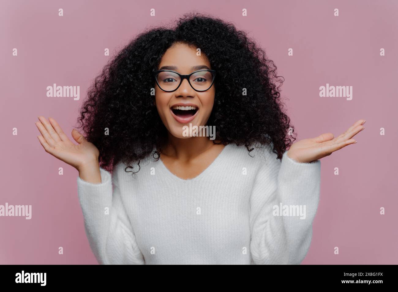 Exuberant young woman with curly hair expressing surprise and delight ...