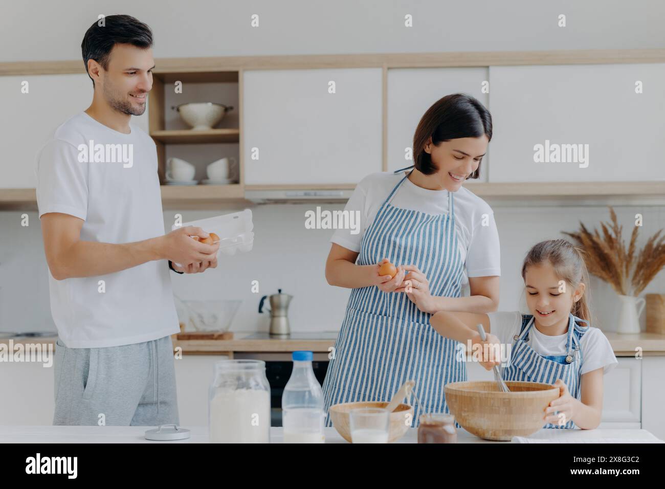 A family cooking time with a father helping while mother and daughter ...