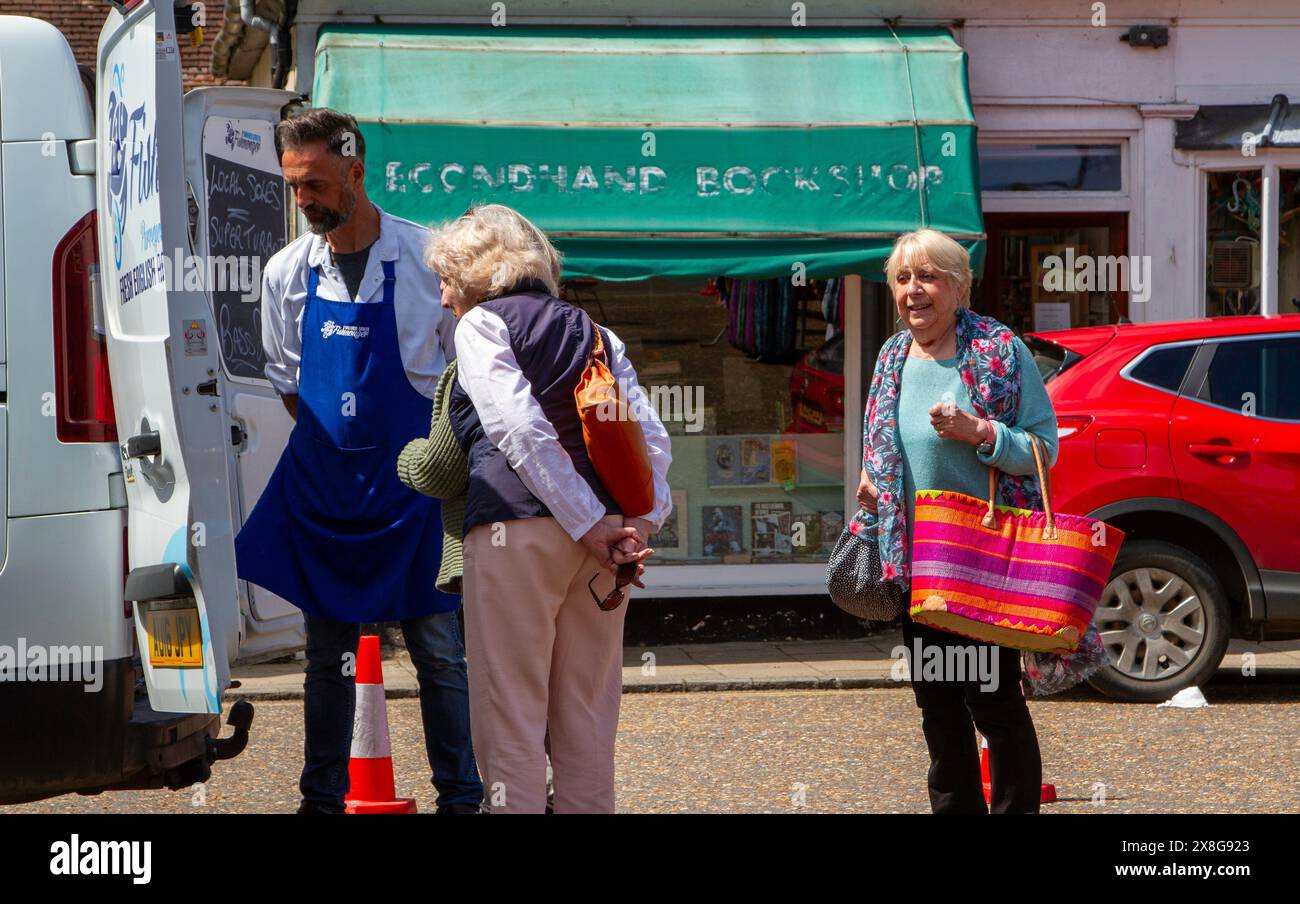On a sunny market day in Framlingham Suffolk a fishmonger in a blue ...