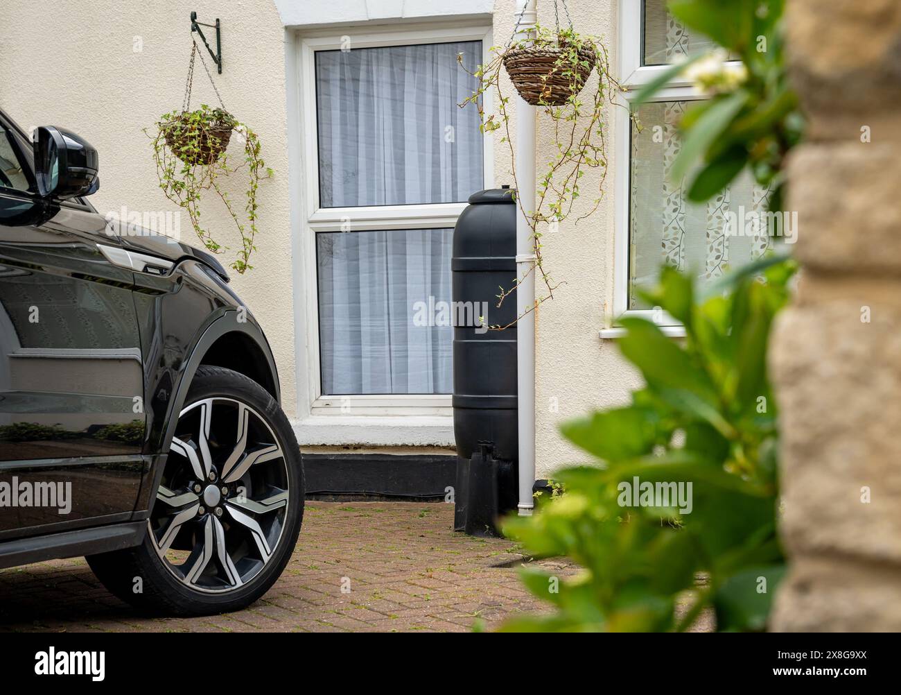 Rain barrel in front of a modern home, rainwater tank for eco friendly ...