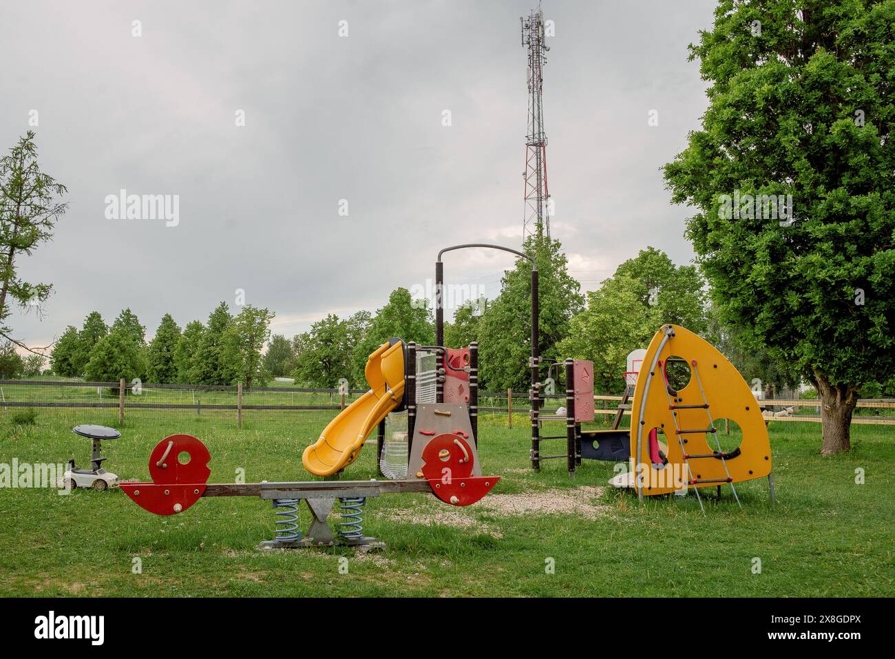 A colorful playground with a slide and swings is located in the park ...
