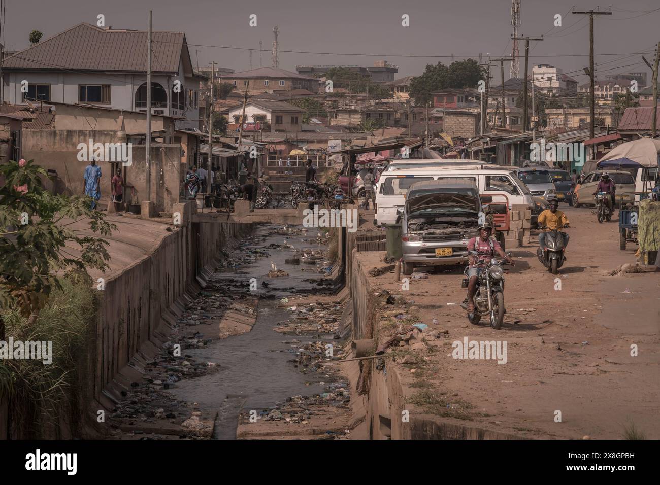 The African people and Ghanian men on motorcycles on the dirty streets ...