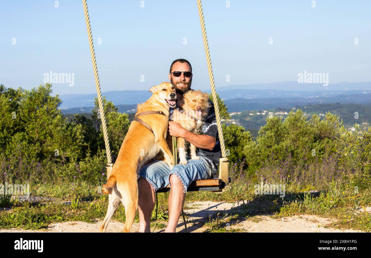 2 Beige coloured dogs hanging out with their person on a large swing in ...