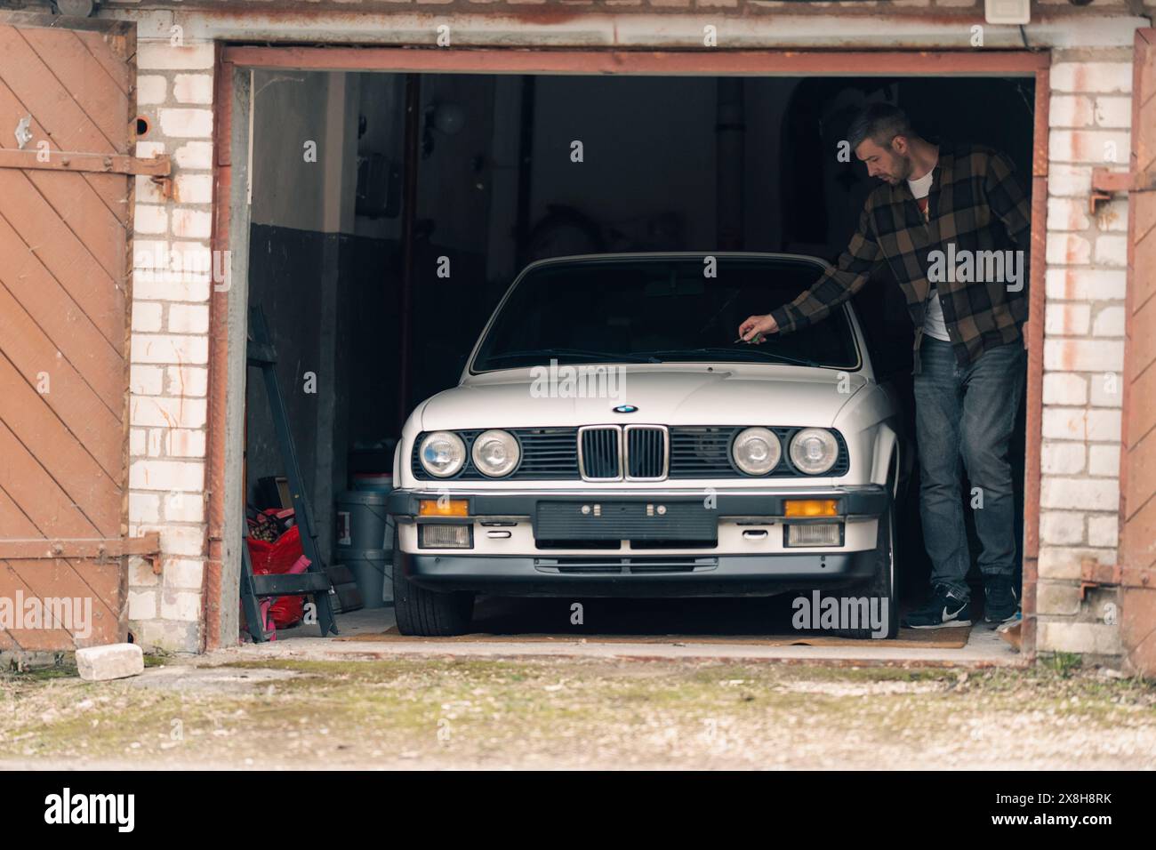 Riga, Latvia - April 1, 2024: A car owner looking on his white classic ...