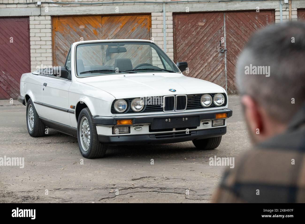 Riga, Latvia - April 1, 2024: A man looking on his white classic ...