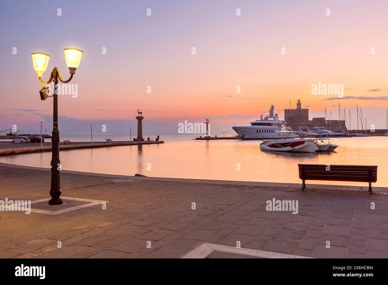 Mandraki Harbor at sunset in Rhodes, Greece, featuring yacht, deer ...