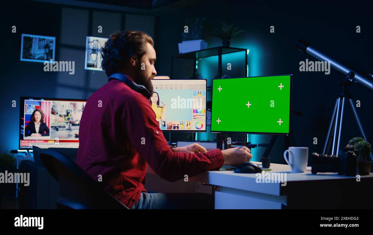 Photographer uses photo editing software on green screen PC display in ...