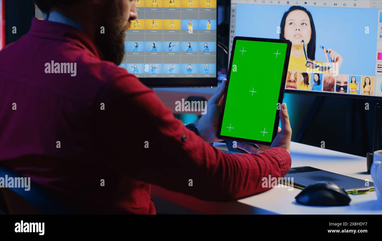 Photo editor learning from tutorial on green screen tablet while ...