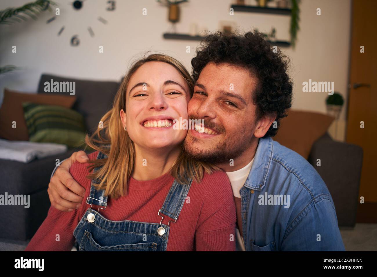 Portrait two cheerful young in love looking at smiling camera in living room. Caucasian happy ...