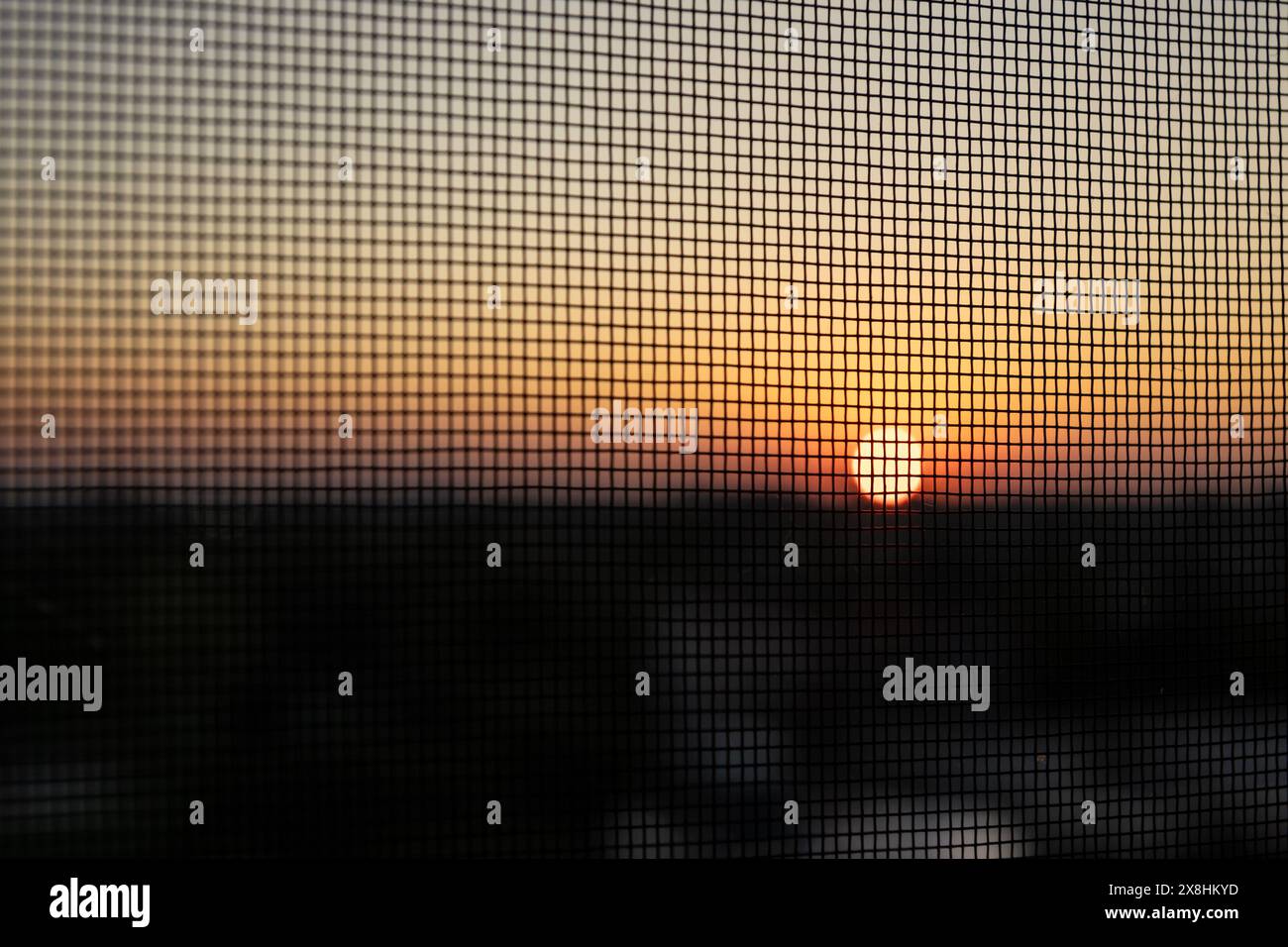 Sunset viewed through a screen - warm hues of orange and yellow ...