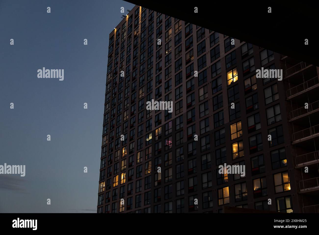 Evening sky backdrop - illuminated windows of a tall apartment building ...