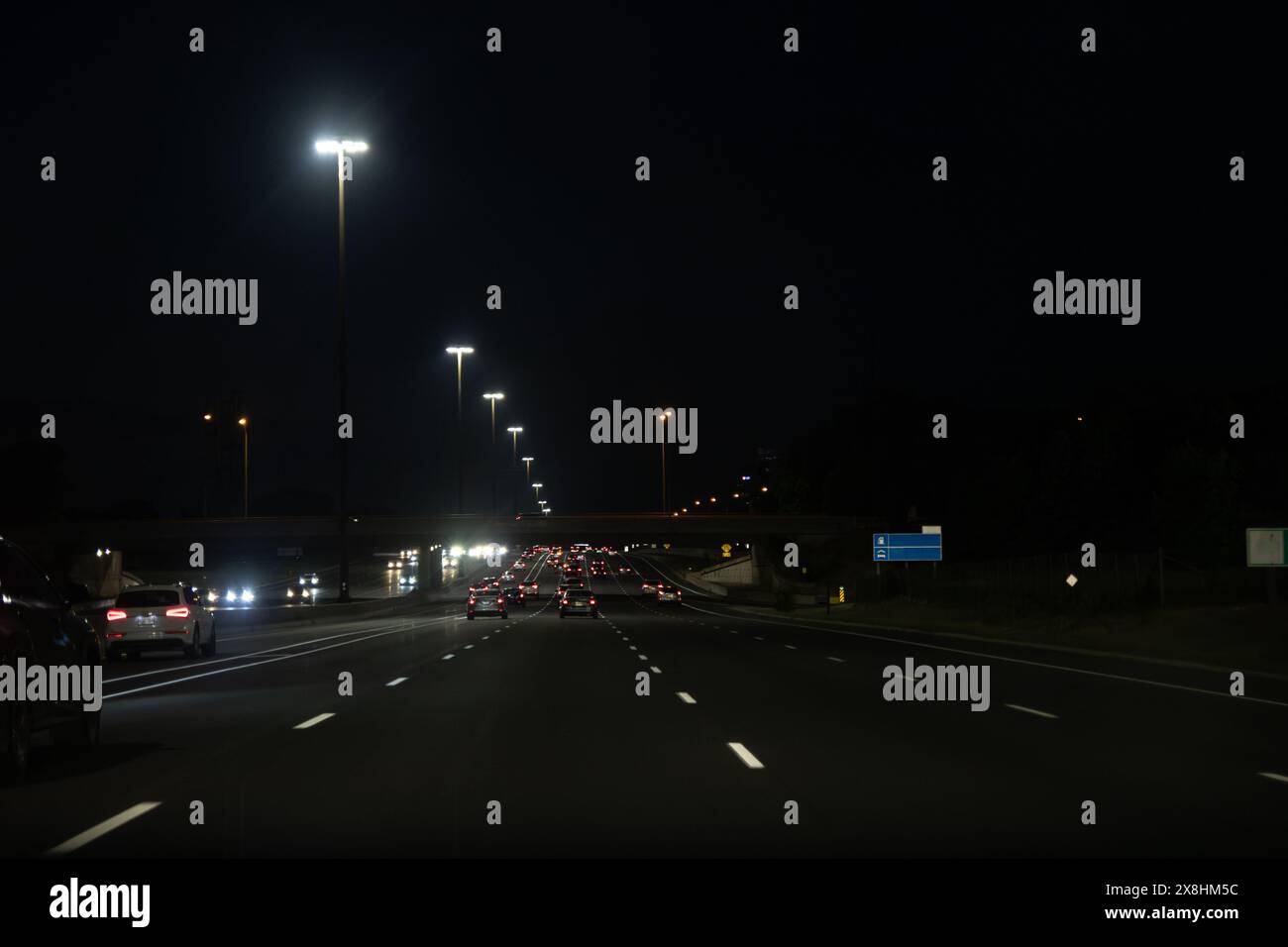 Nighttime highway - illuminated by streetlights - cars with tail lights ...