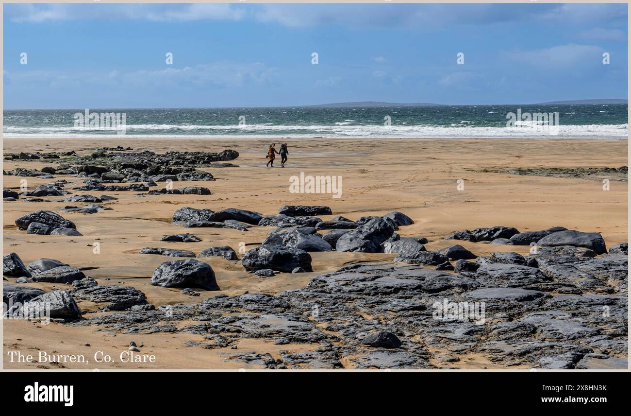 Irish beach in County Clare with unusual black rocks and a couple ...