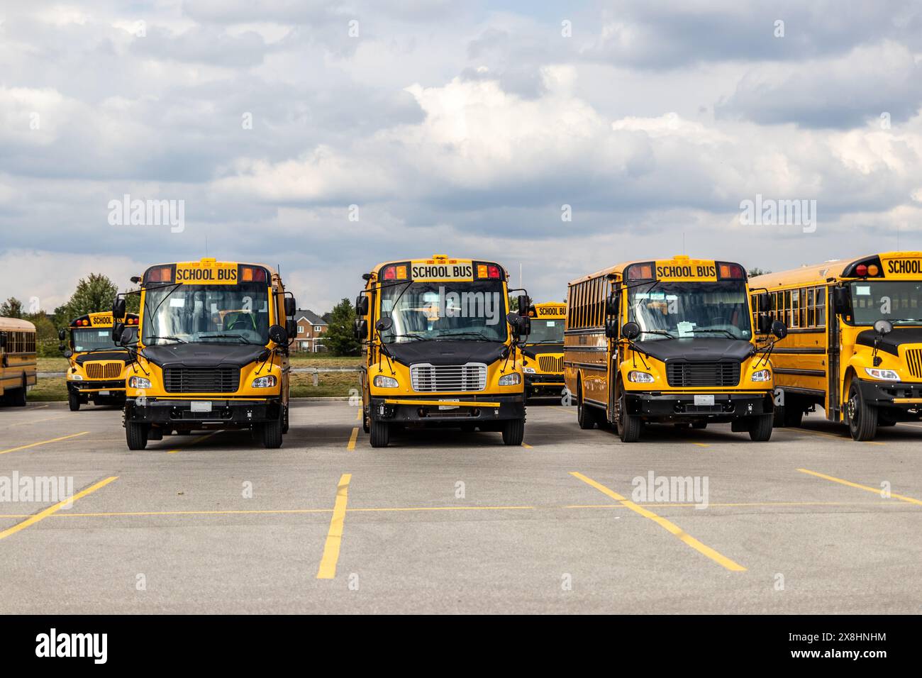 Yellow school buses lined up in an empty parking lot - under a partly ...
