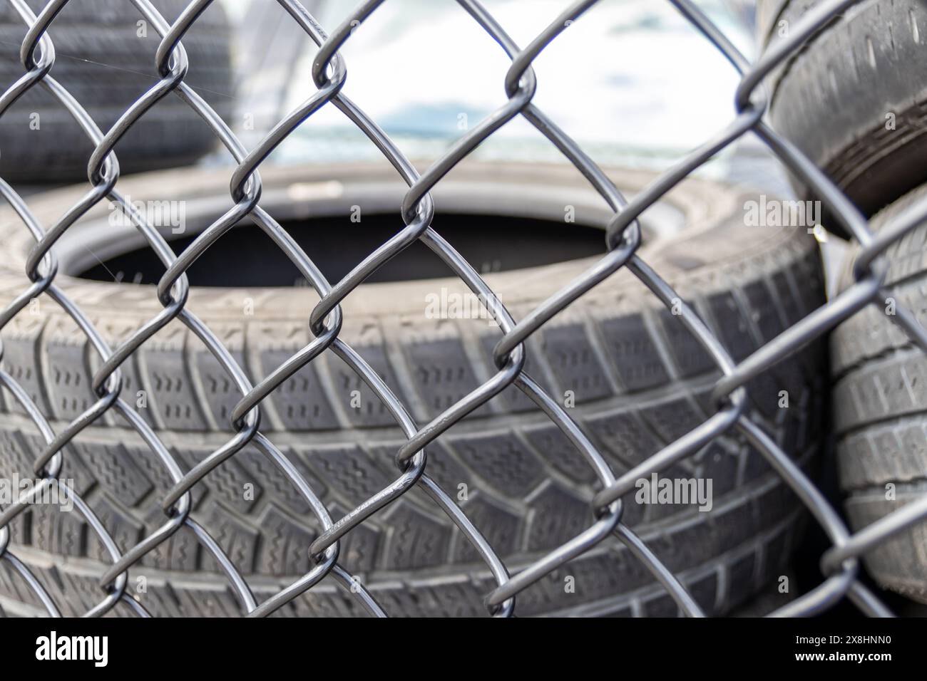 Stacked used tires - visible through a chain-link fence - focus on ...