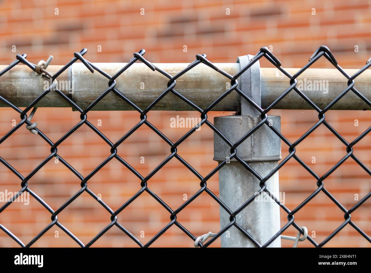 Close-up view - chain-link fence - weathered metal post - orange brick ...
