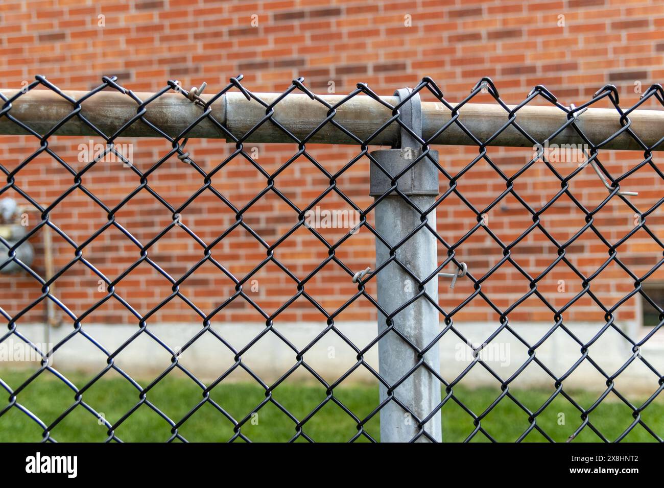 Close-up view - chain-link fence - weathered metal post - orange brick ...