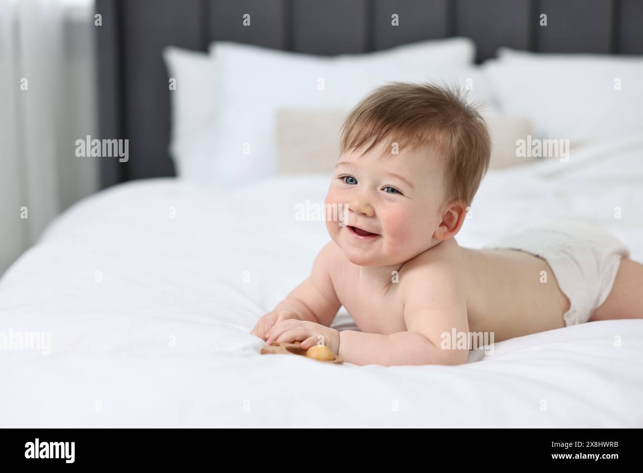 Cute baby boy with rattle lying on bed at home. Space for text Stock ...
